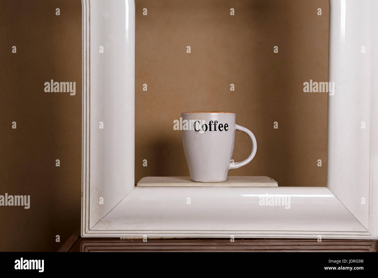 Mug of coffee placed in white painting frame. Cropped studio photo ...