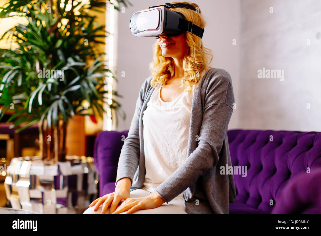 Attractive blond woman wearing headset virtual reality vision goggles ...