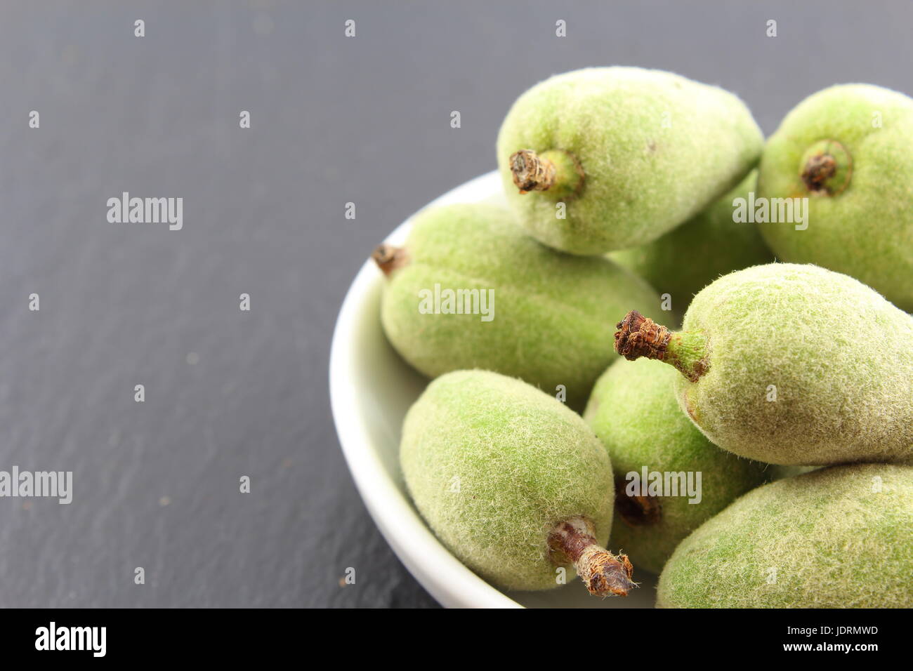 composition of fresh green almond fruits in a small white bowl Stock ...