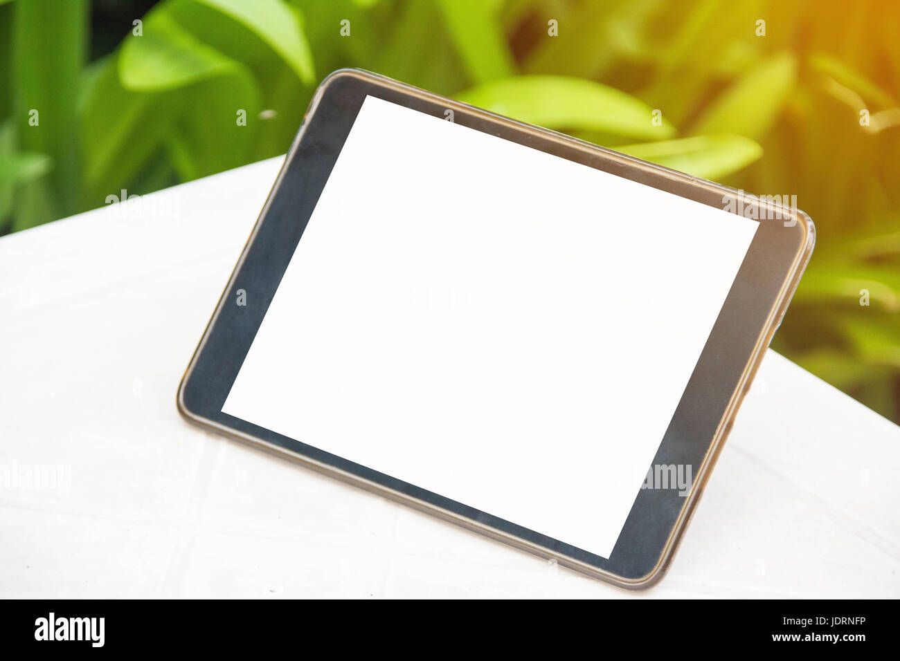 white screen tablet on white table with nature background. soft focus ...