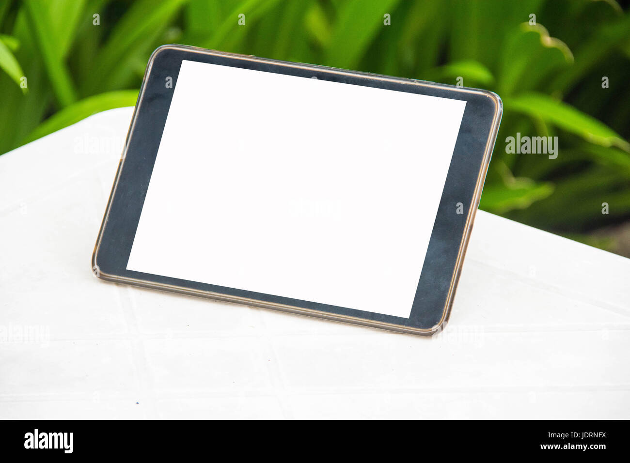 white screen tablet on white table with nature background. soft focus ...