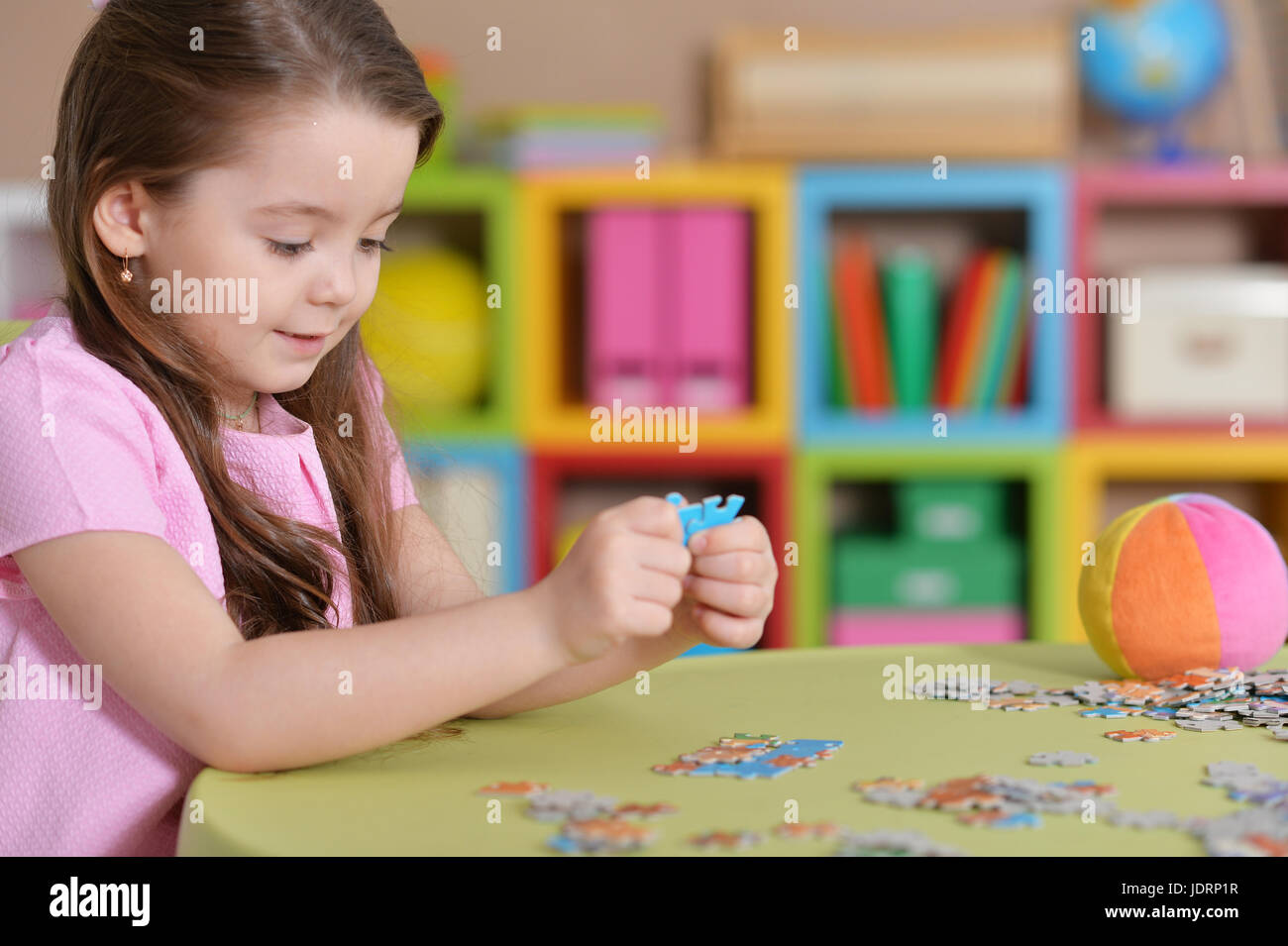 Portrait of a cute little girl collecting puzzles Stock Photo - Alamy