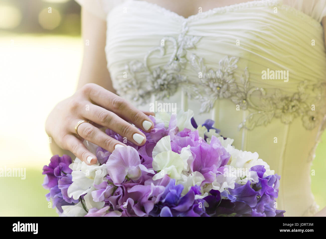 Hands of just married couple with golden wedding rings and sweet pea ...