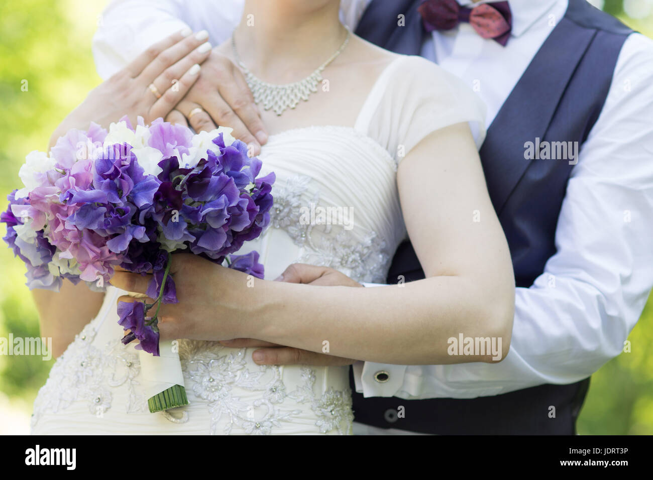 Young just married couple hugging on their wedding day with sweet pea ...