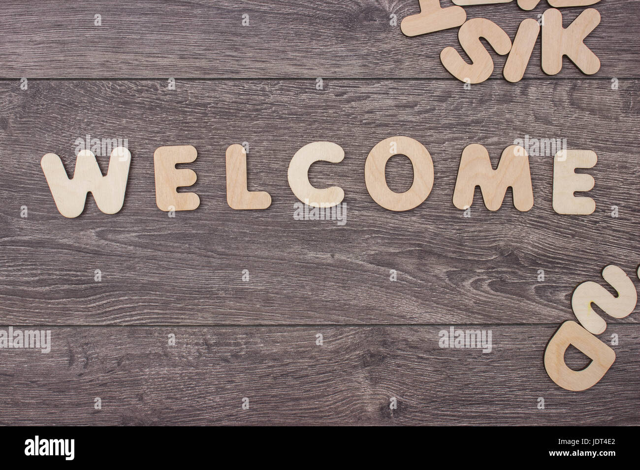 Word Welcome made with wooden letters next to a pile of other letters ...
