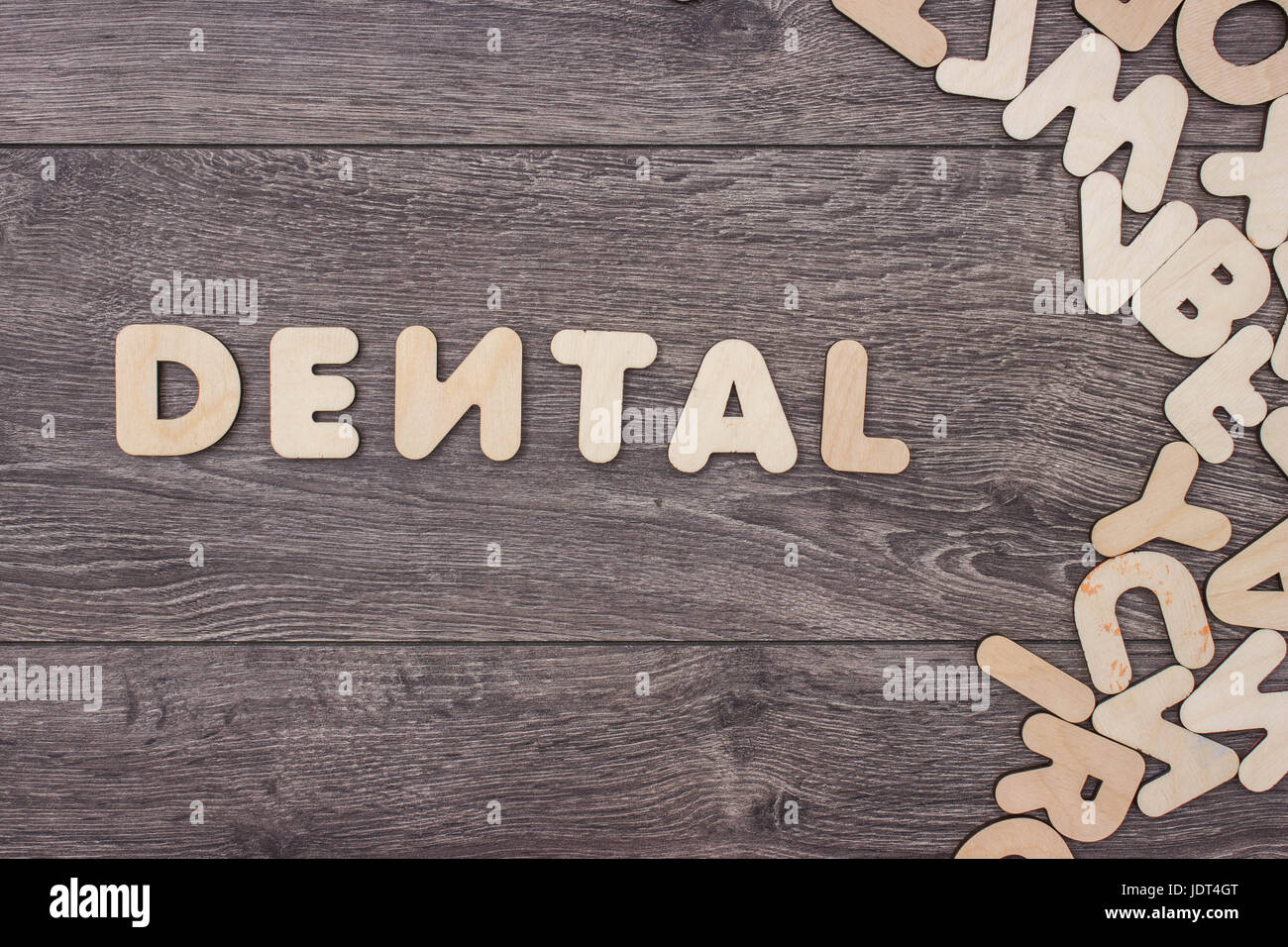 Word Dental made with wooden letters next to a pile of other letters ...