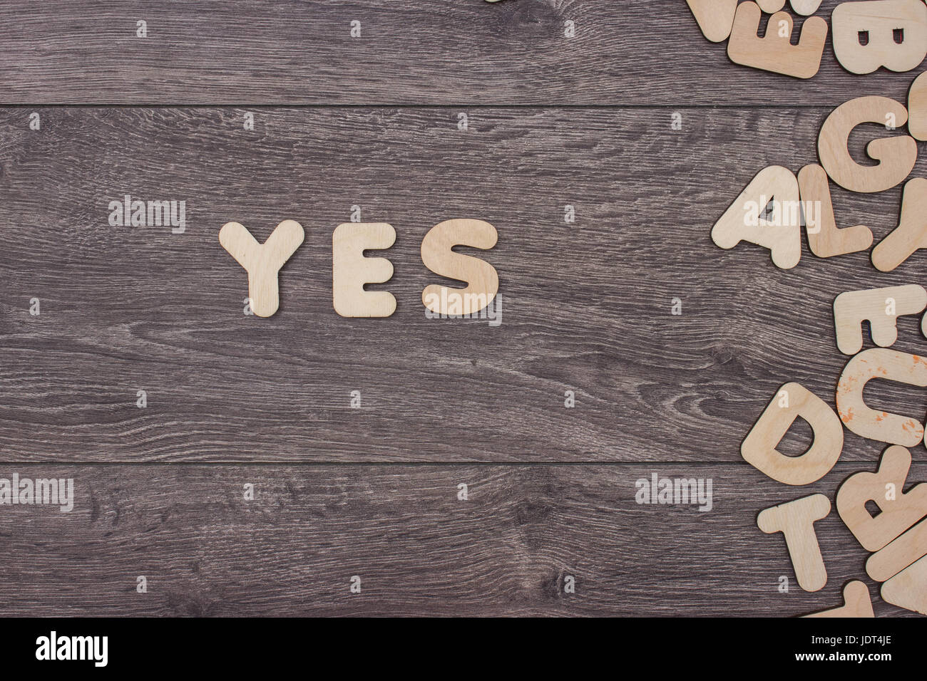 Word Yes made with wooden letters next to a pile of other letters over ...