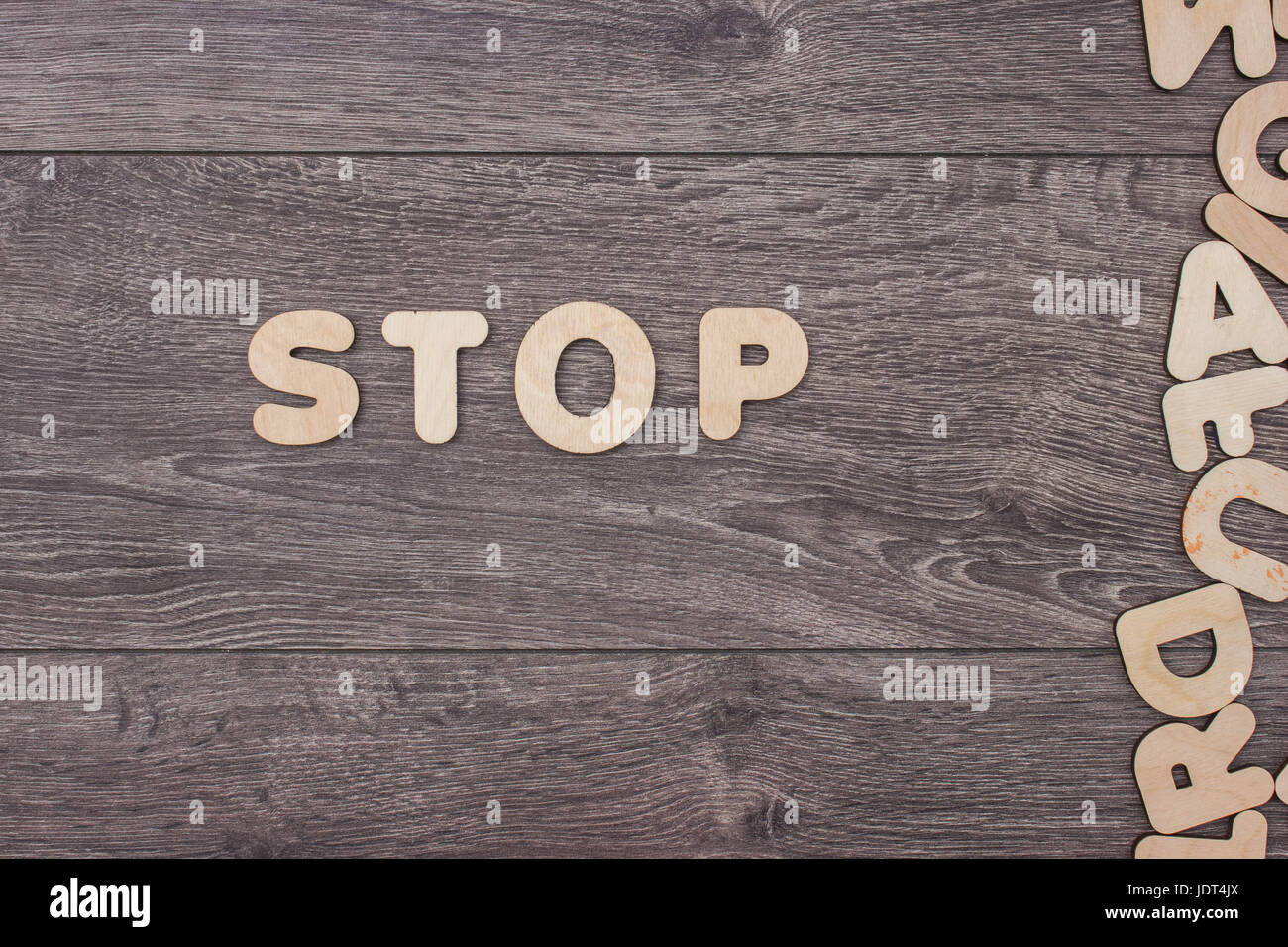 Word Stop made with wooden letters next to a pile of other letters over ...