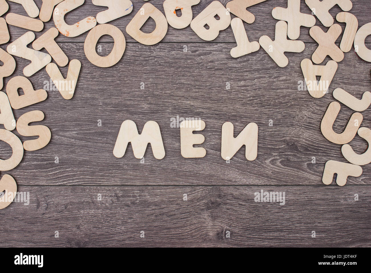Word Men made with wooden letters next to a pile of other letters over ...