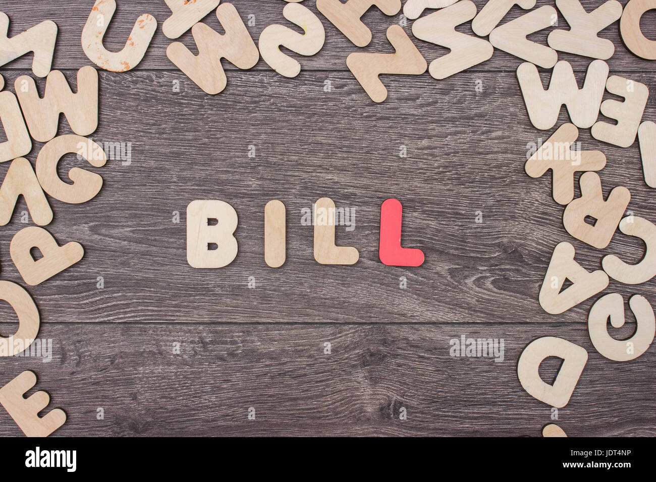 Word bill made with wooden letters next to a pile of other letters over ...