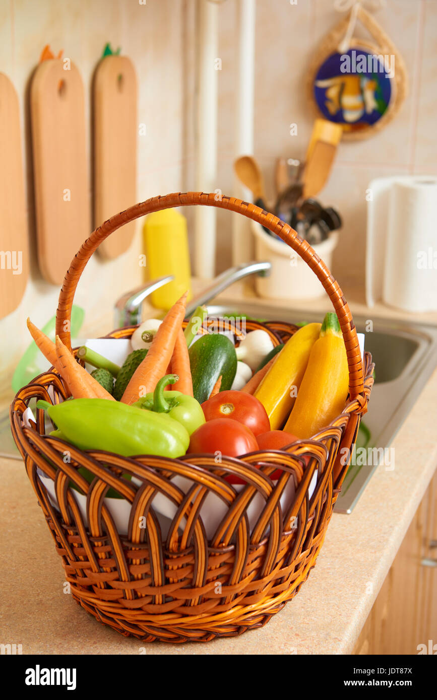 vegetables and fresh greens in basket in kitchen interior, healthy food ...