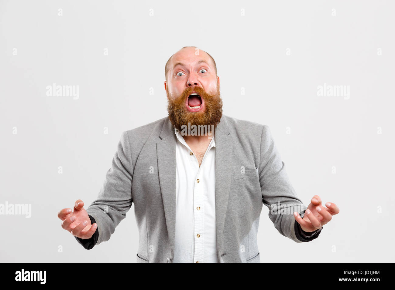 Upset screaming man with ginger beard in gray jacket on empty ...