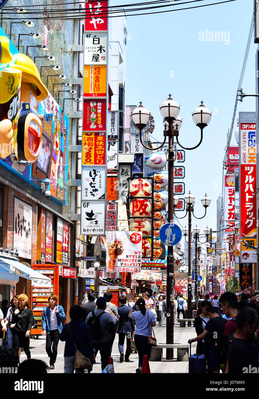 Shoppers stroll down an alleyway of signs and neon lights in Namba ...