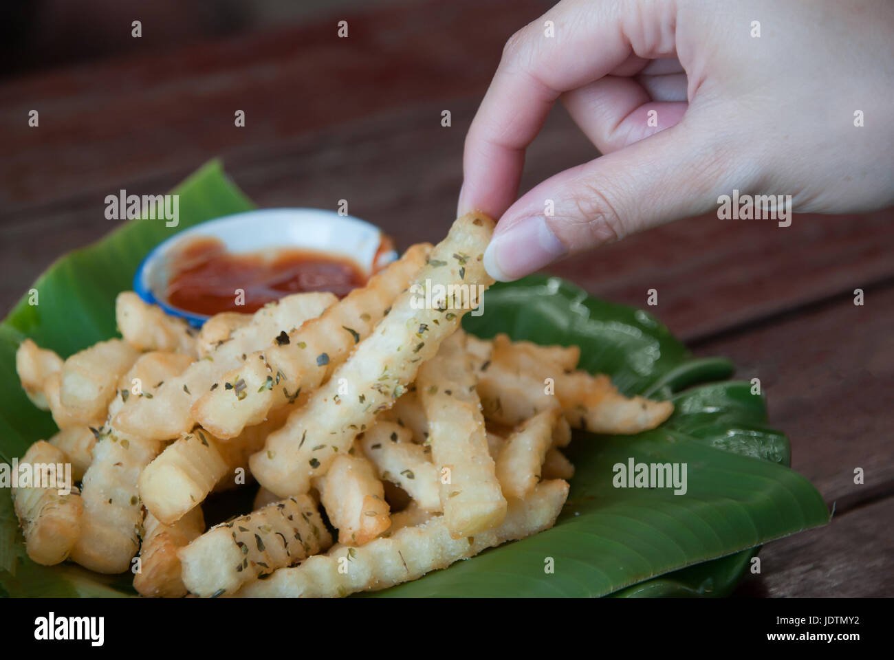 woman hand picking up french fries from dish that decorated on banana ...