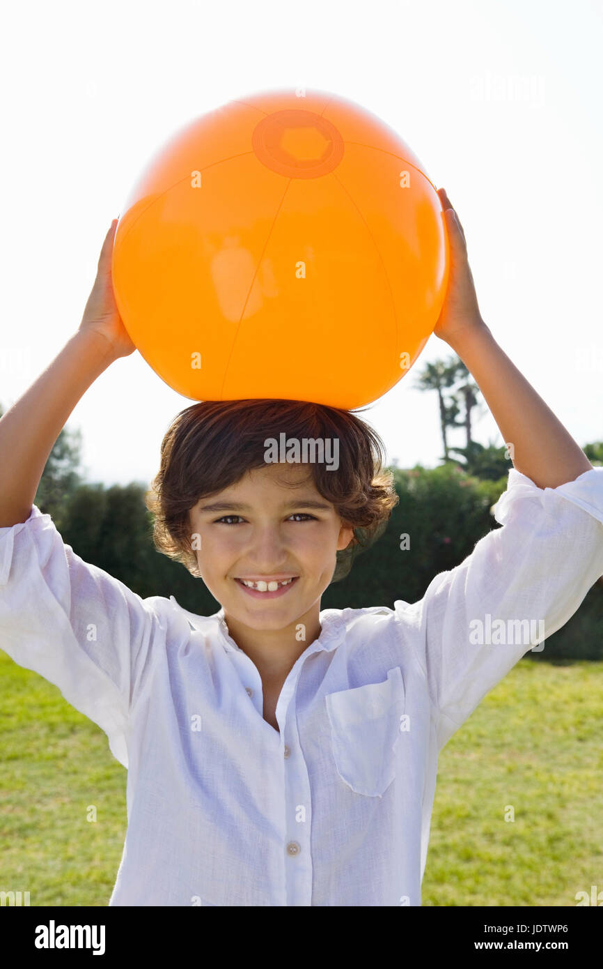 Young kid holds an orange ball over head Stock Photo - Alamy