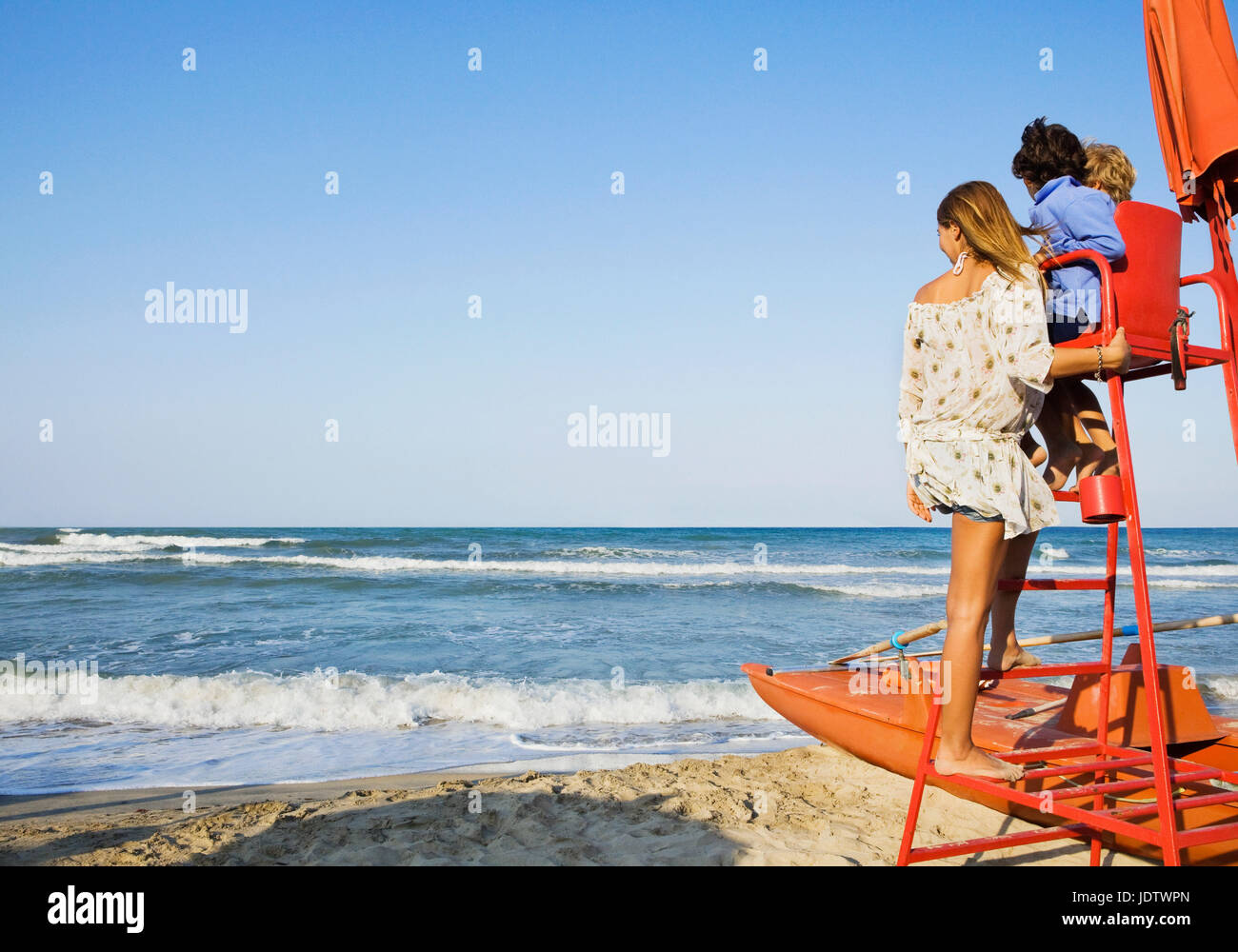 Lady with kids sits on lifeguard podium Stock Photo - Alamy