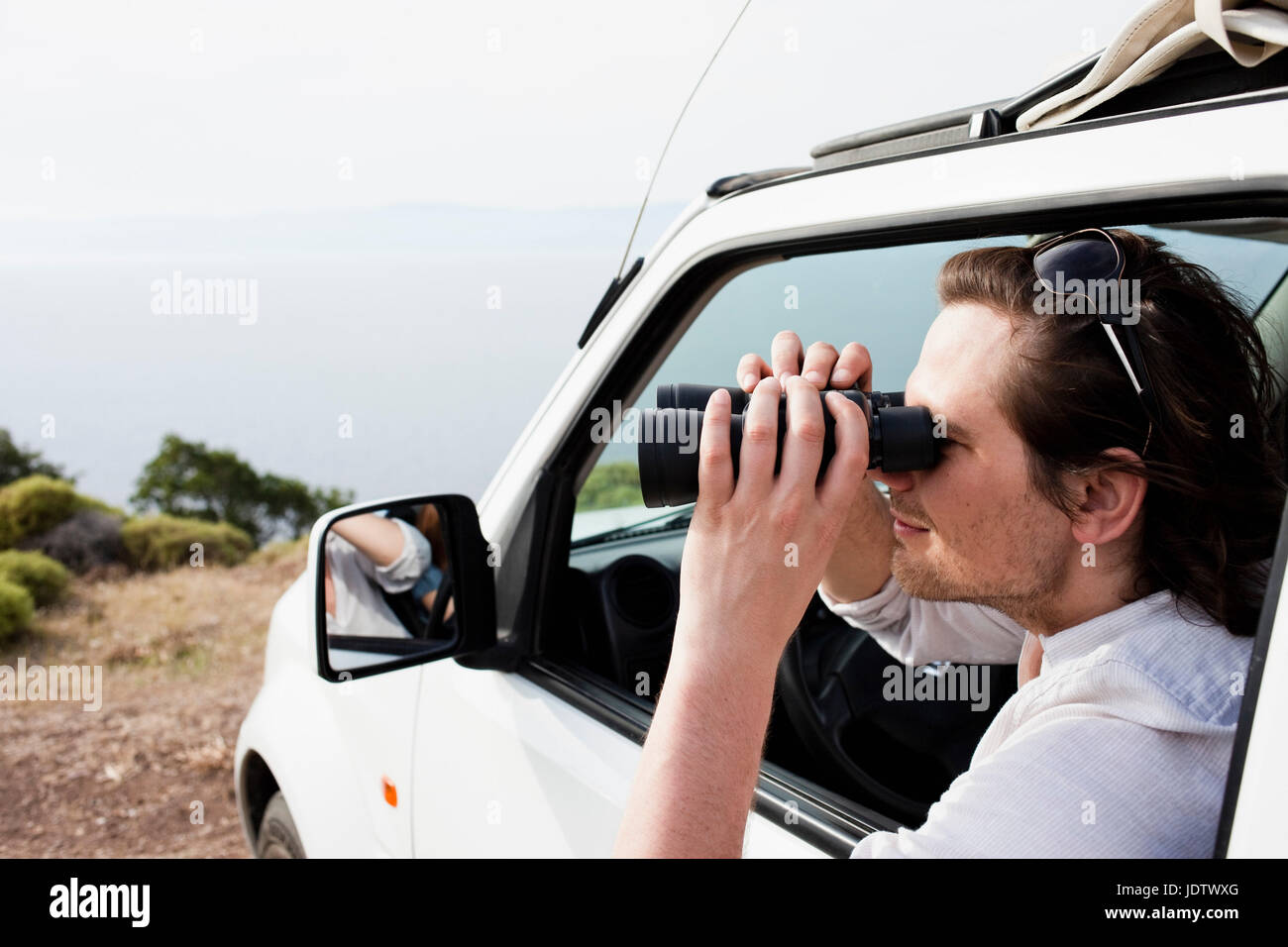 Man in car looking through binoculars Stock Photo - Alamy