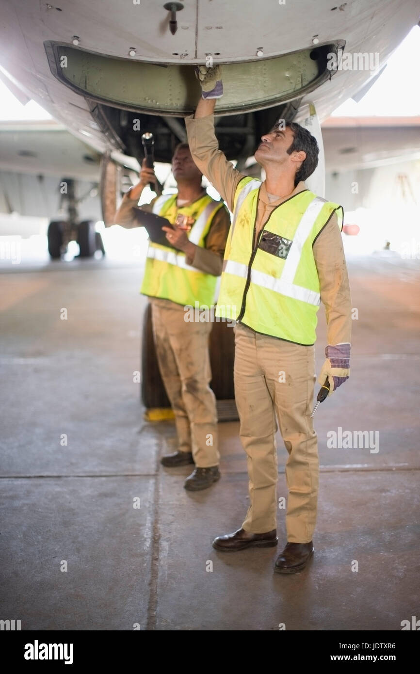 Aircraft workers checking airplane Stock Photo - Alamy