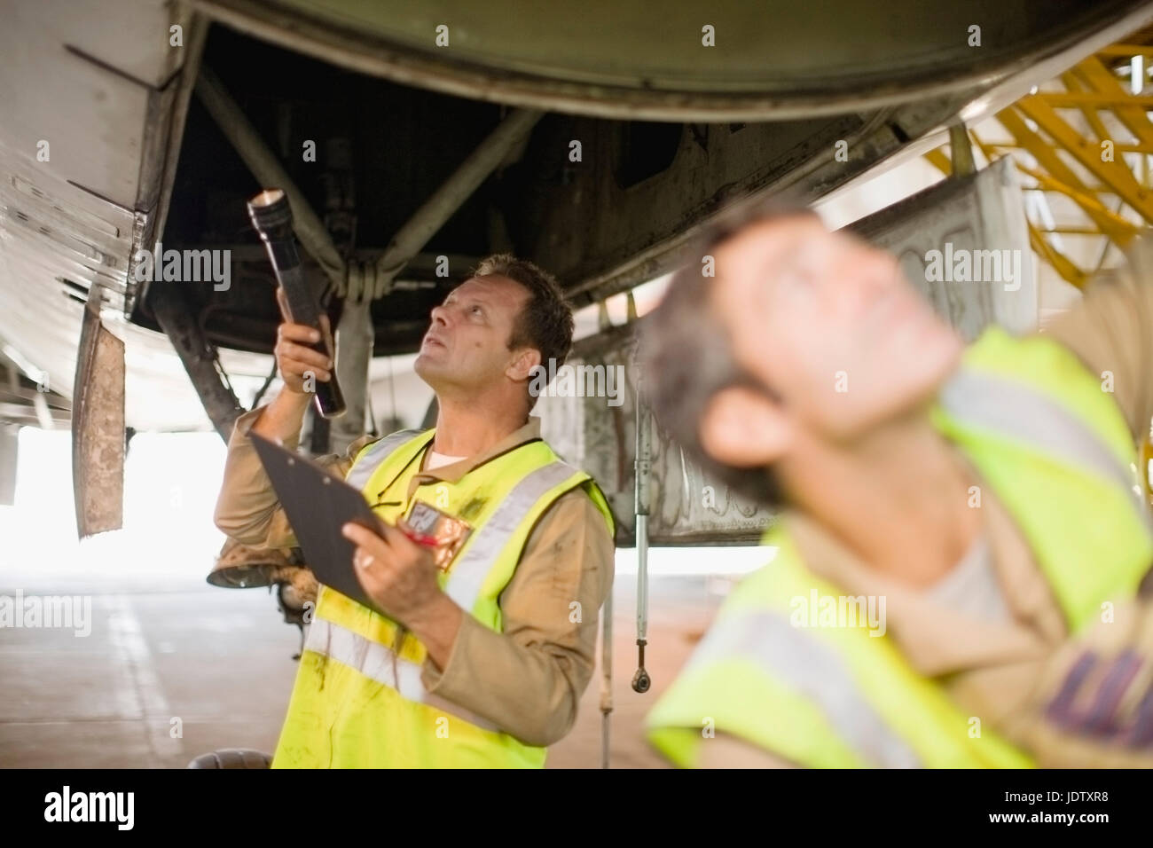Aircraft workers checking airplane Stock Photo - Alamy