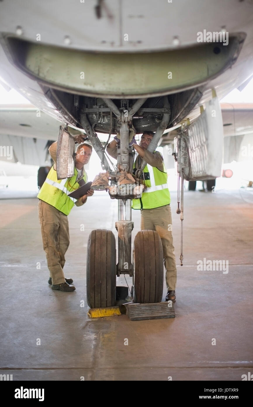 Aircraft workers checking airplane Stock Photo - Alamy