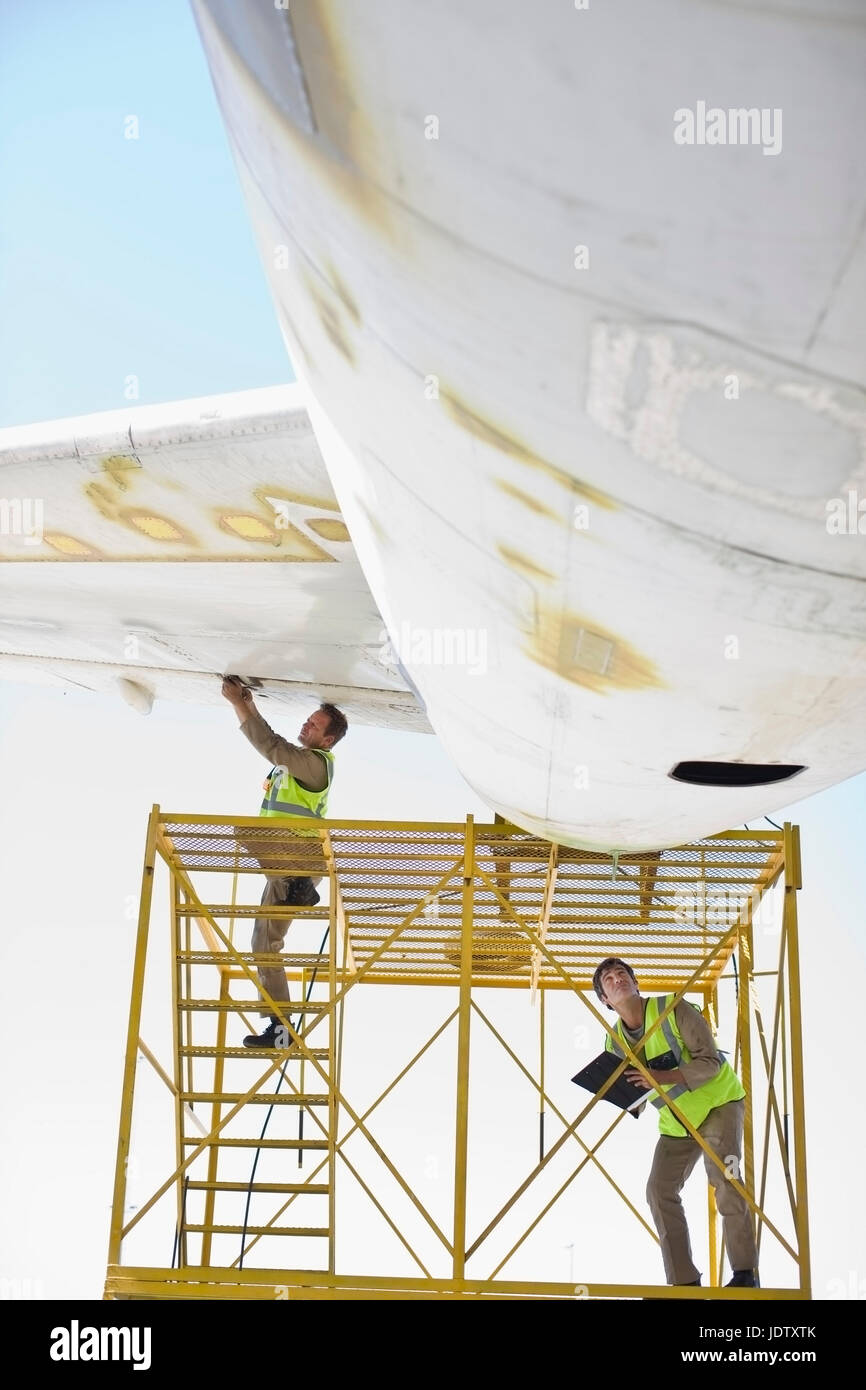 Aircraft workers repairing airplane Stock Photo - Alamy