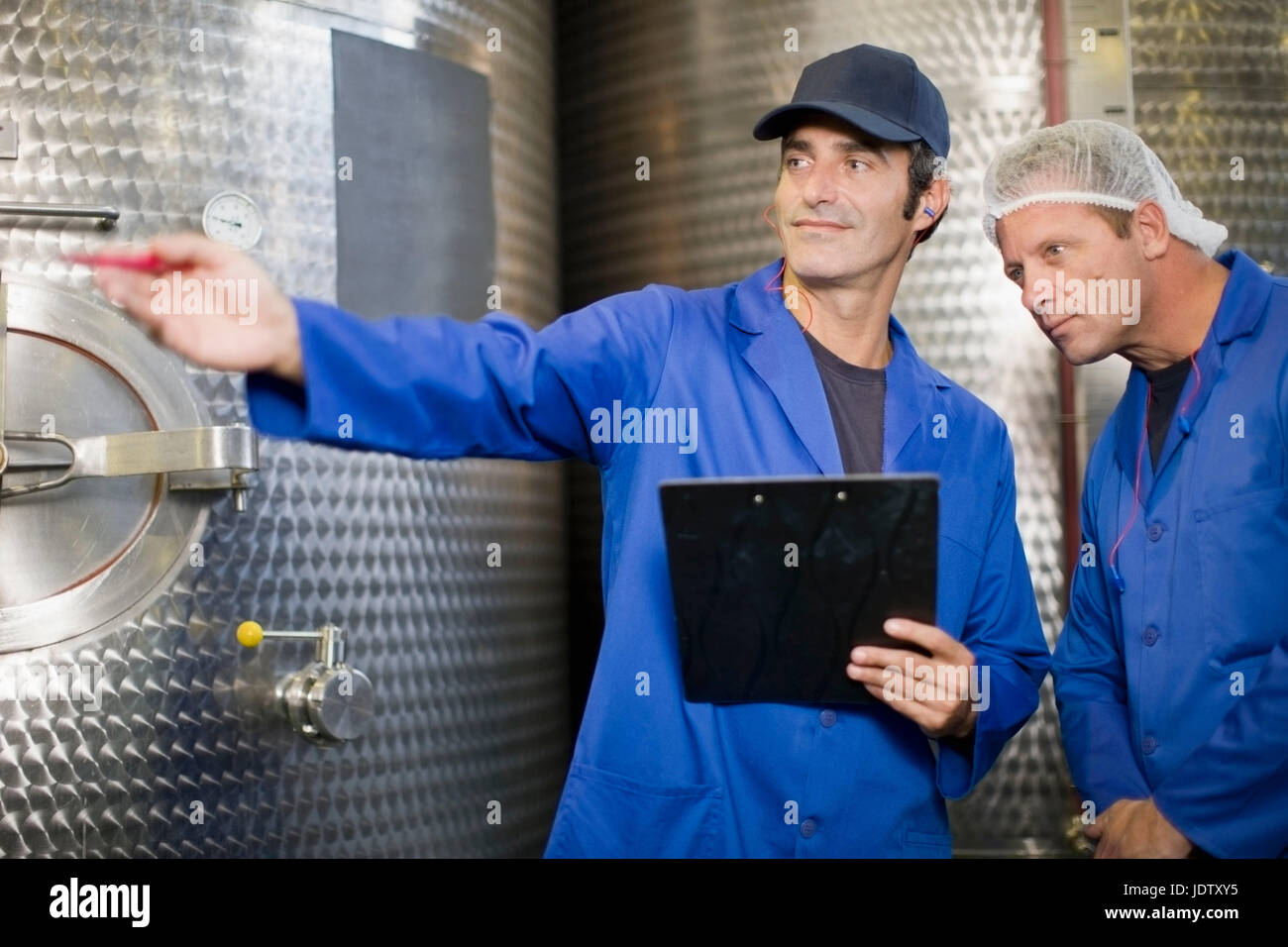 Workers examining machinery in factory Stock Photo - Alamy