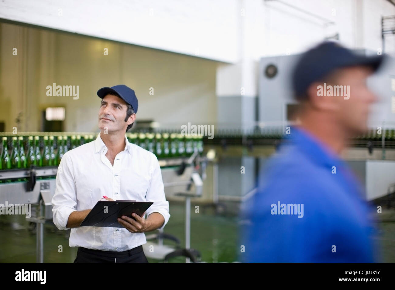 Worker writing on clipboard in factory Stock Photo - Alamy
