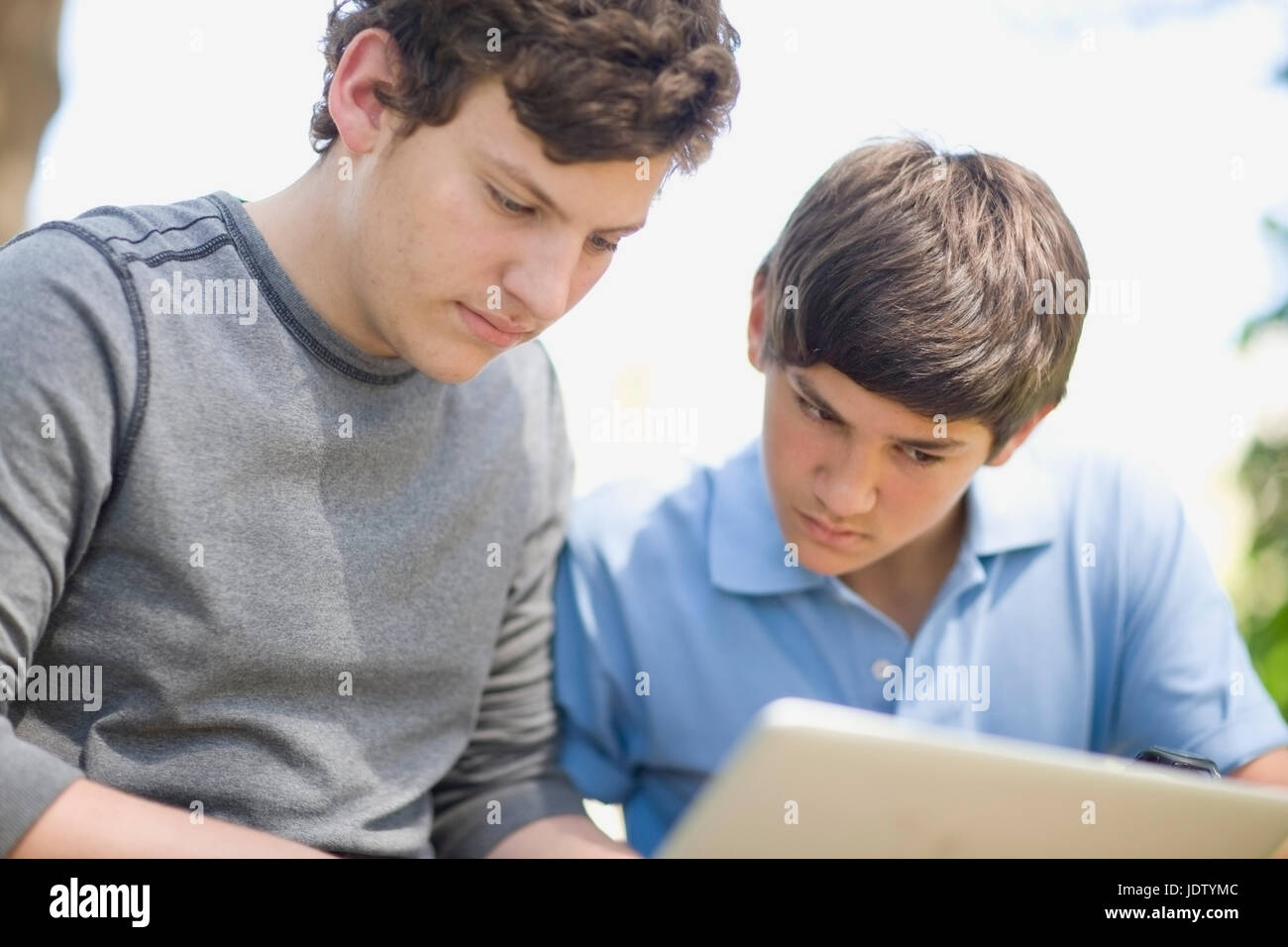 Teenage boys using laptop together Stock Photo - Alamy