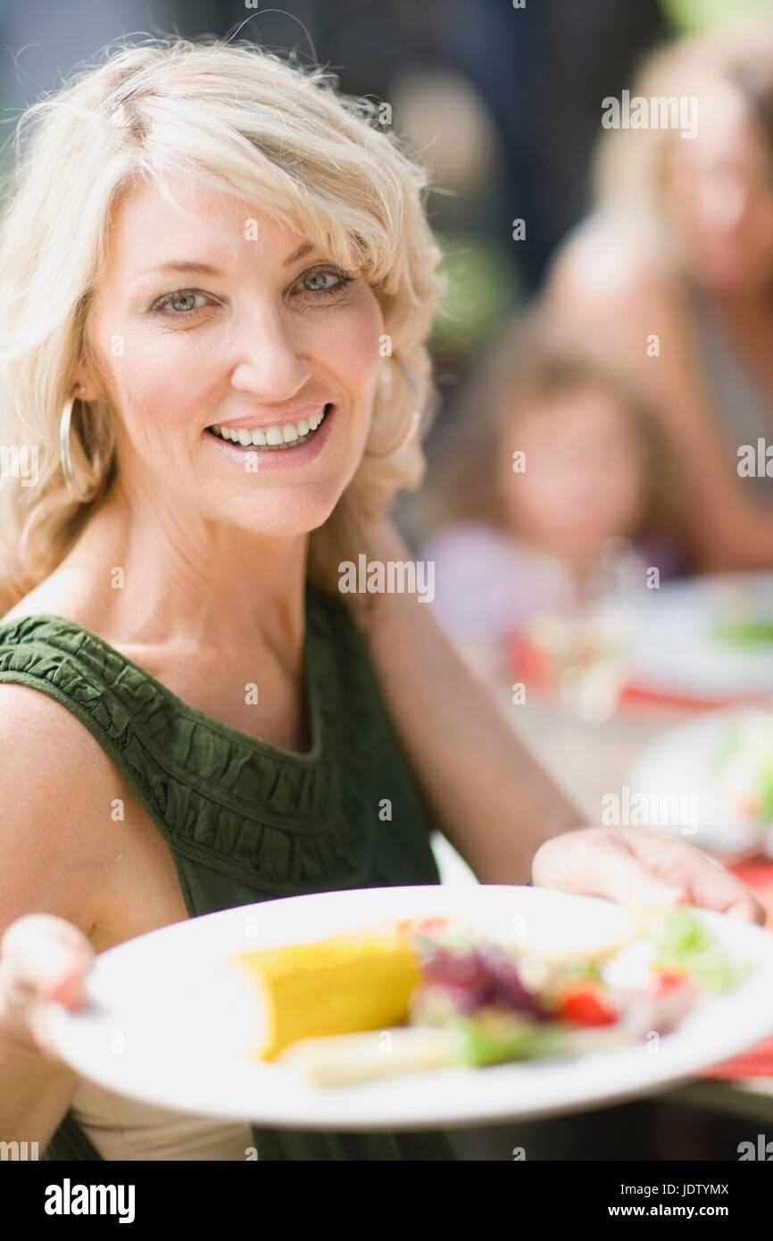 Woman offering plate of food outdoors Stock Photo - Alamy