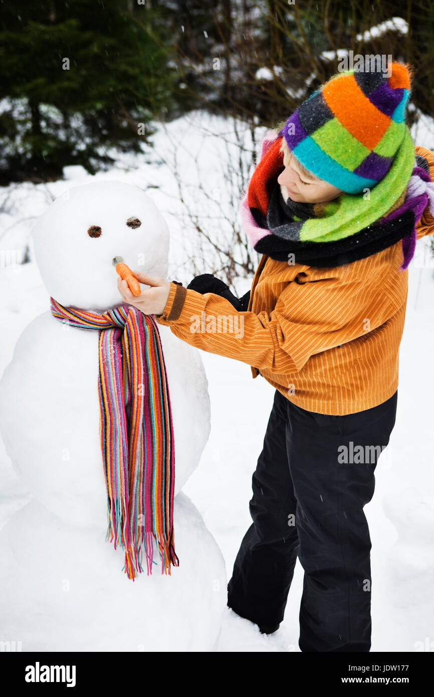 Boy making snowman in meadow Stock Photo - Alamy