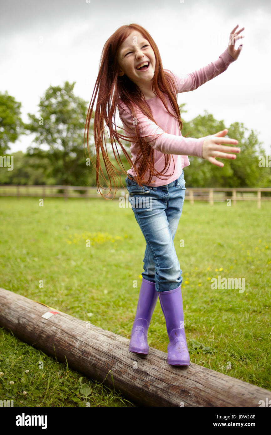 Girl balancing on wooden log Stock Photo - Alamy