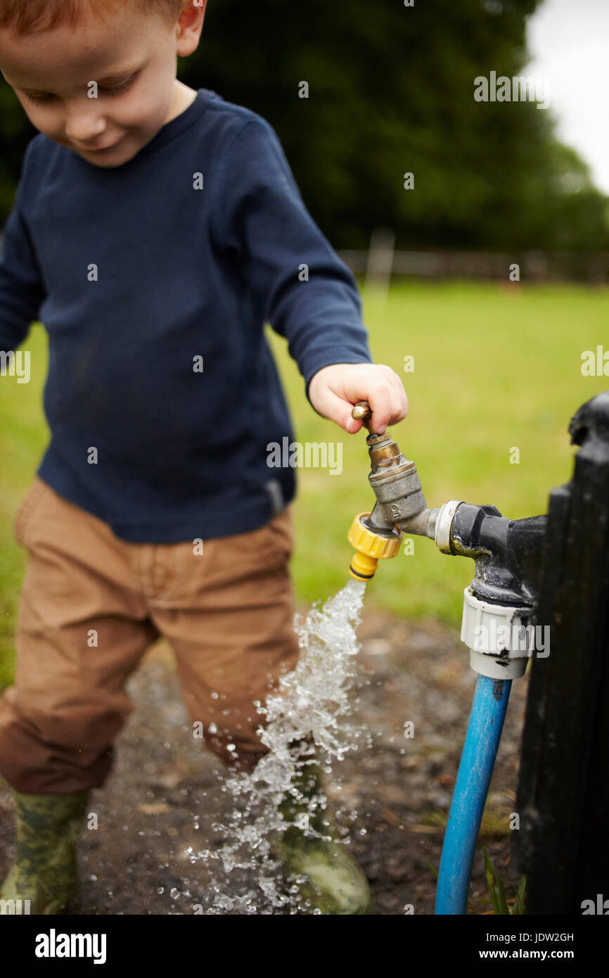 Boy playing with spout outdoors Stock Photo - Alamy