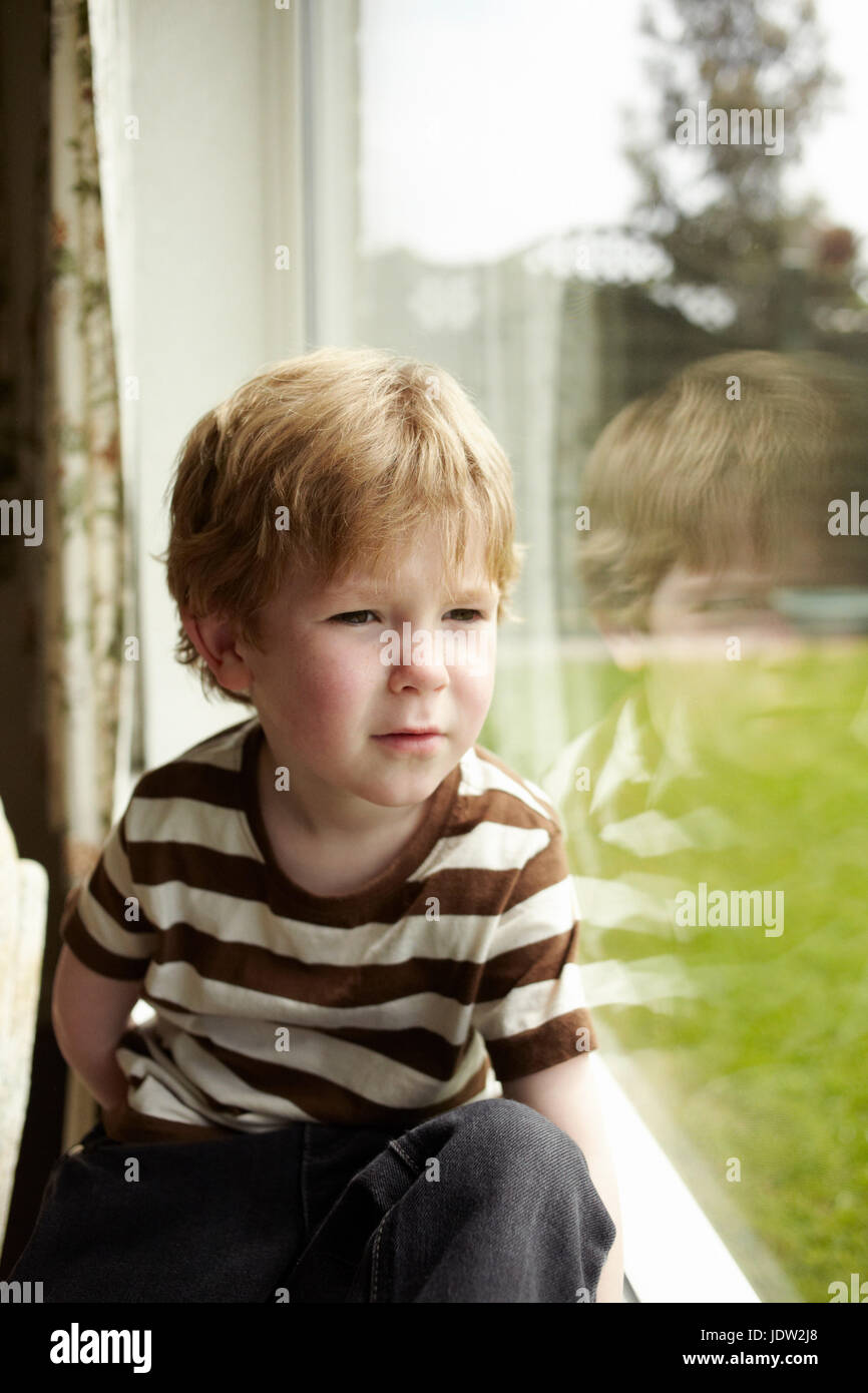 Boy looking out window at backyard Stock Photo - Alamy