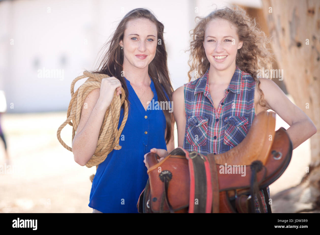 Young women carrying saddle and rope Stock Photo - Alamy