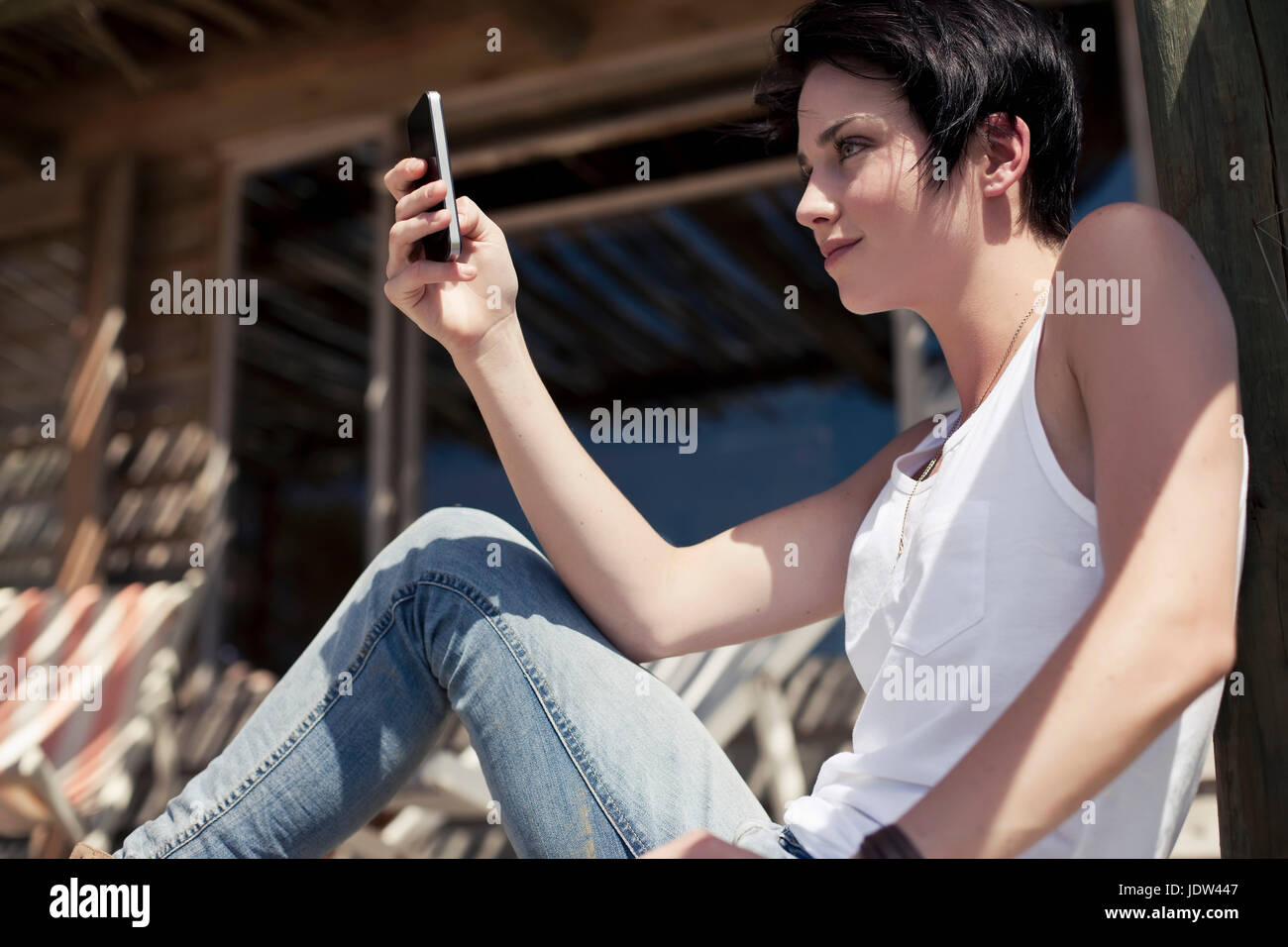 Young woman sitting outside using smart phone Stock Photo - Alamy