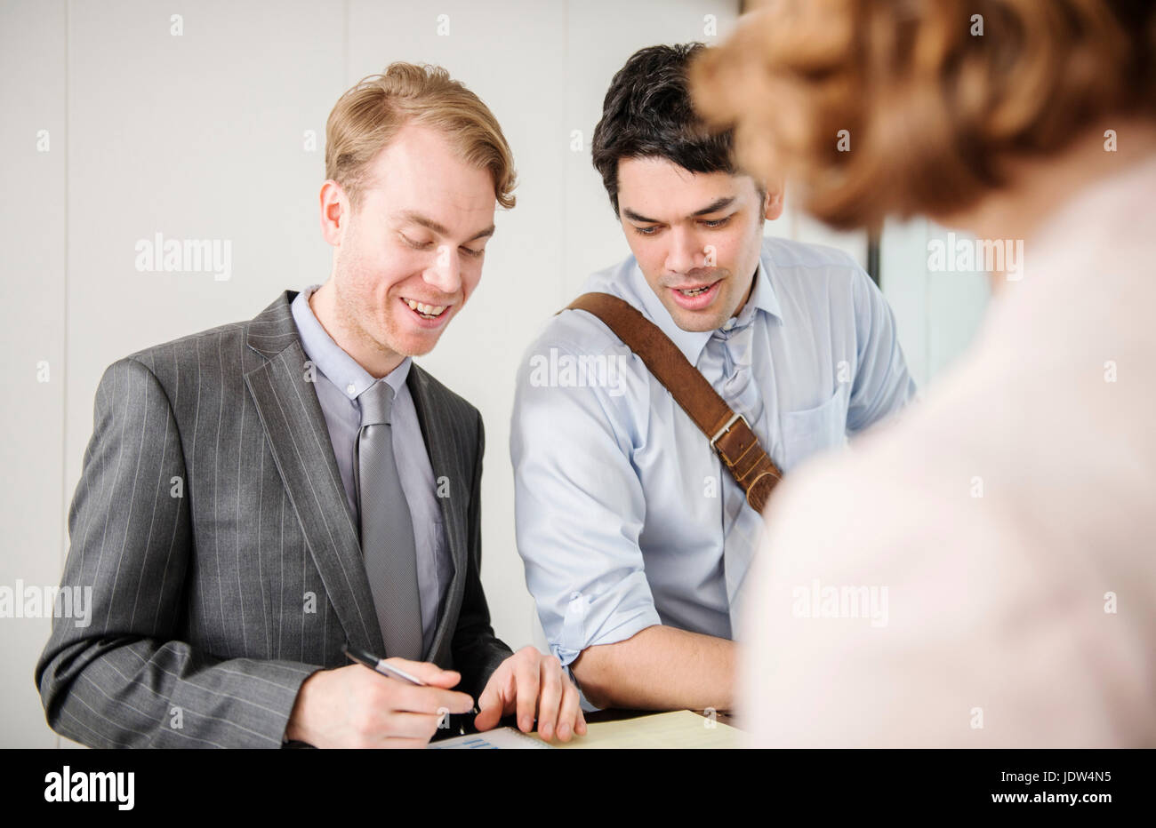Two men signing form at reception Stock Photo - Alamy