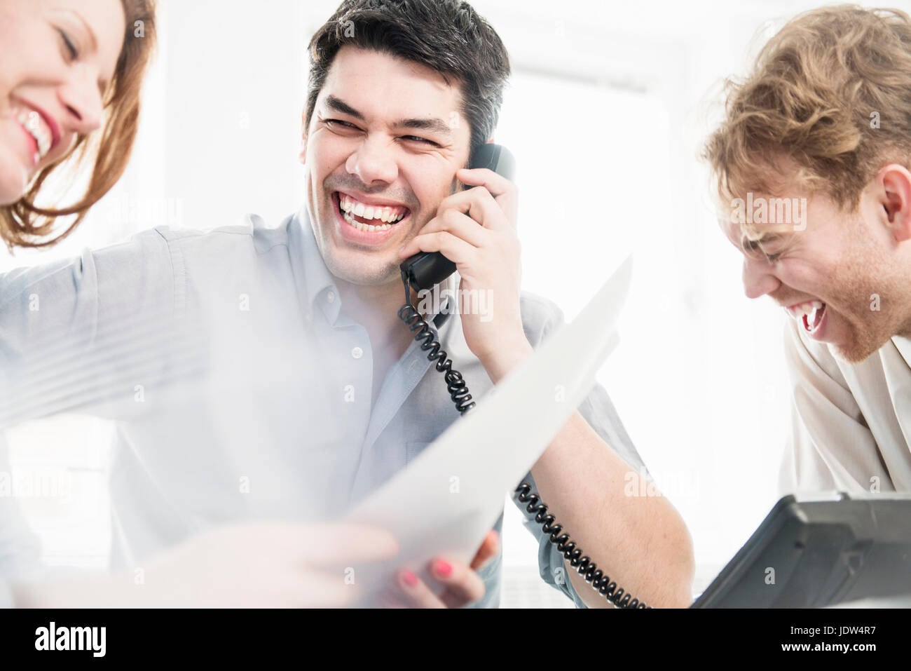 Man on telephone laughing with colleagues Stock Photo - Alamy
