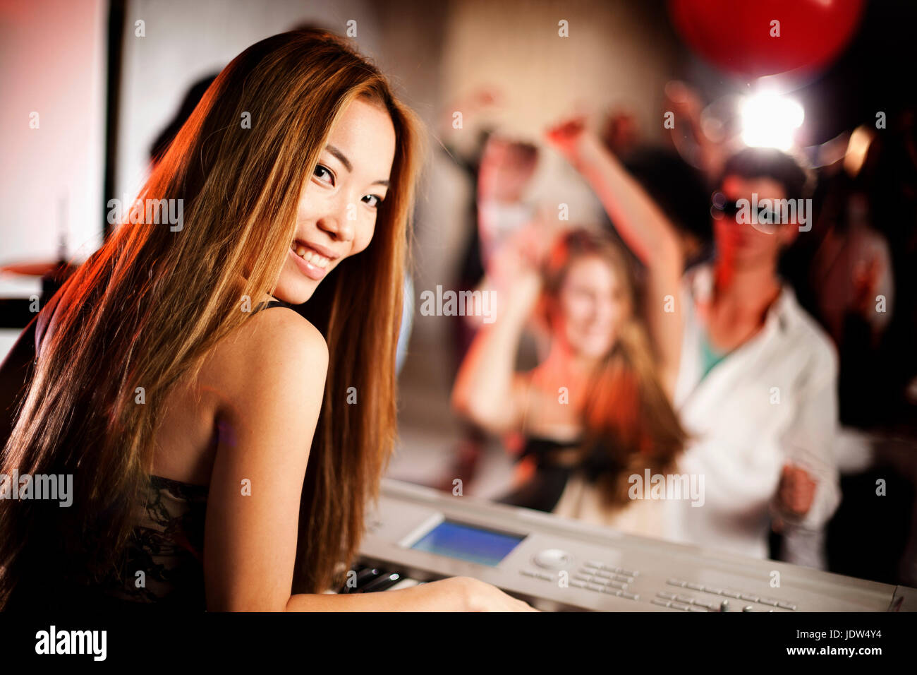 Young woman playing keyboard with people dancing Stock Photo - Alamy