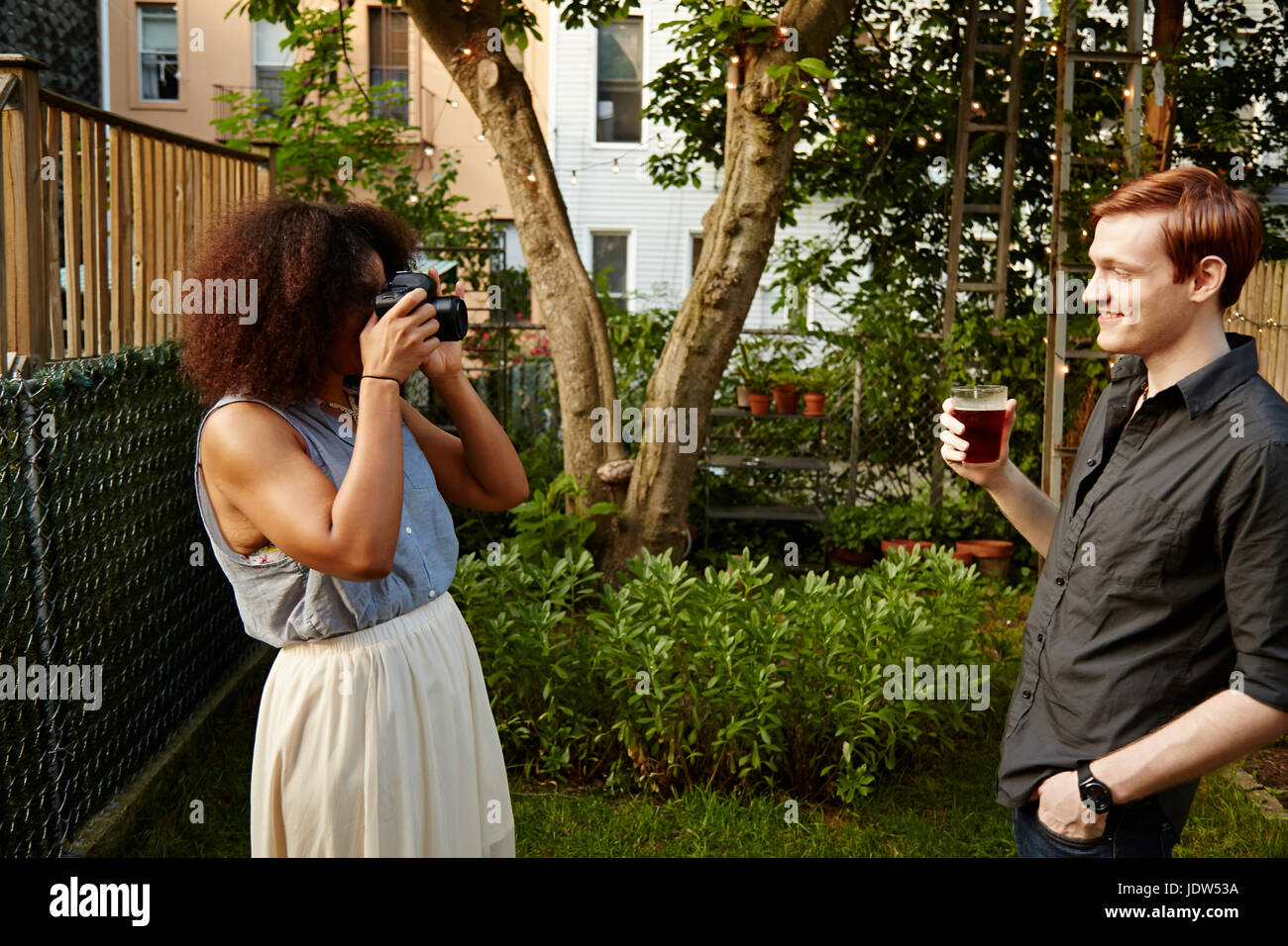 Young woman photographing man in garden Stock Photo - Alamy