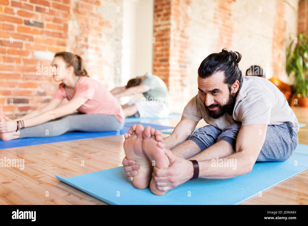 group of people doing yoga forward bend at studio Stock Photo - Alamy