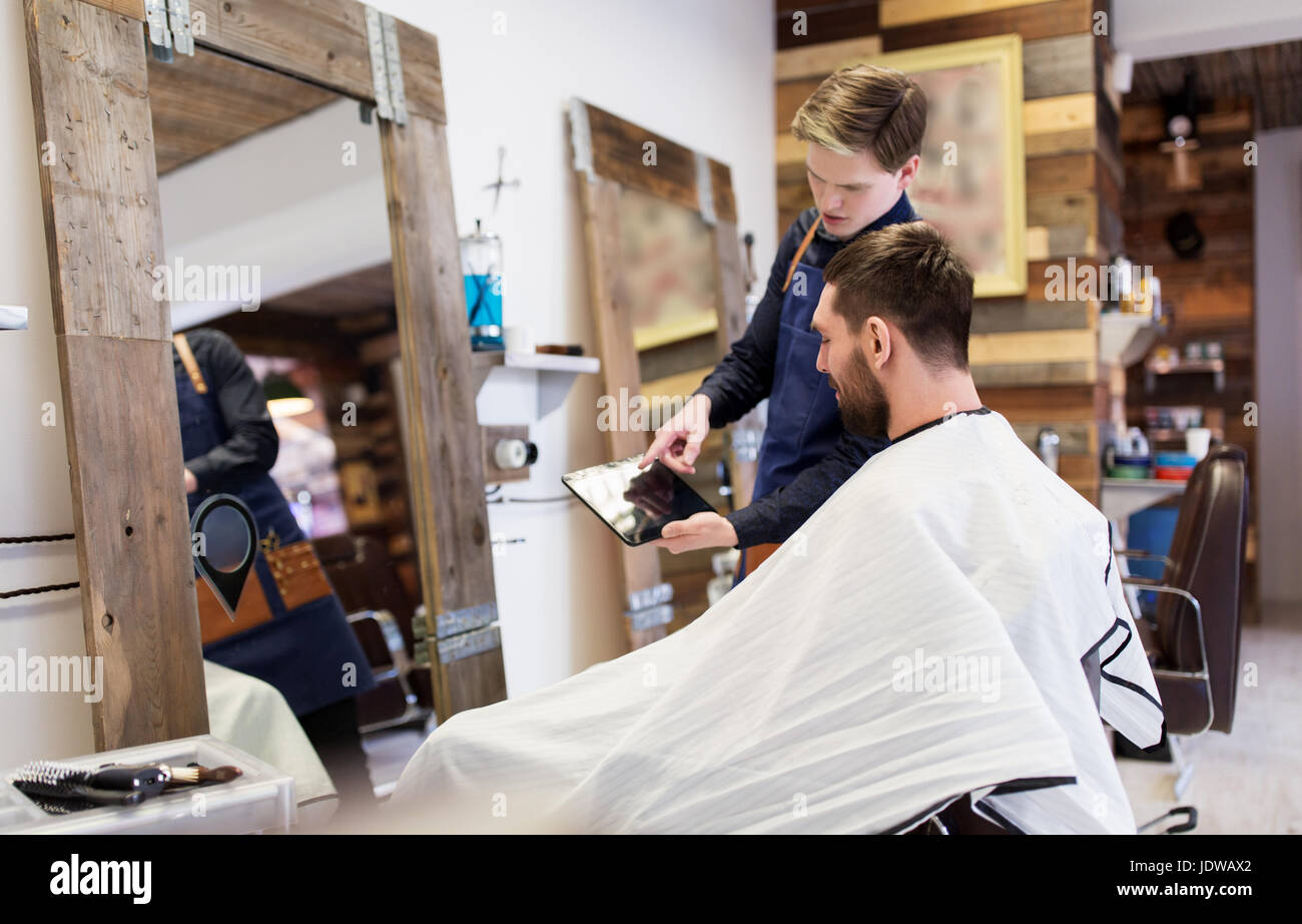 barber showing tablet pc to man at barbershop Stock Photo - Alamy