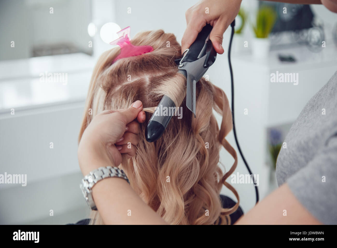 Hair stylist makes a curls for a girl, using hair styling. Hairdresser ...