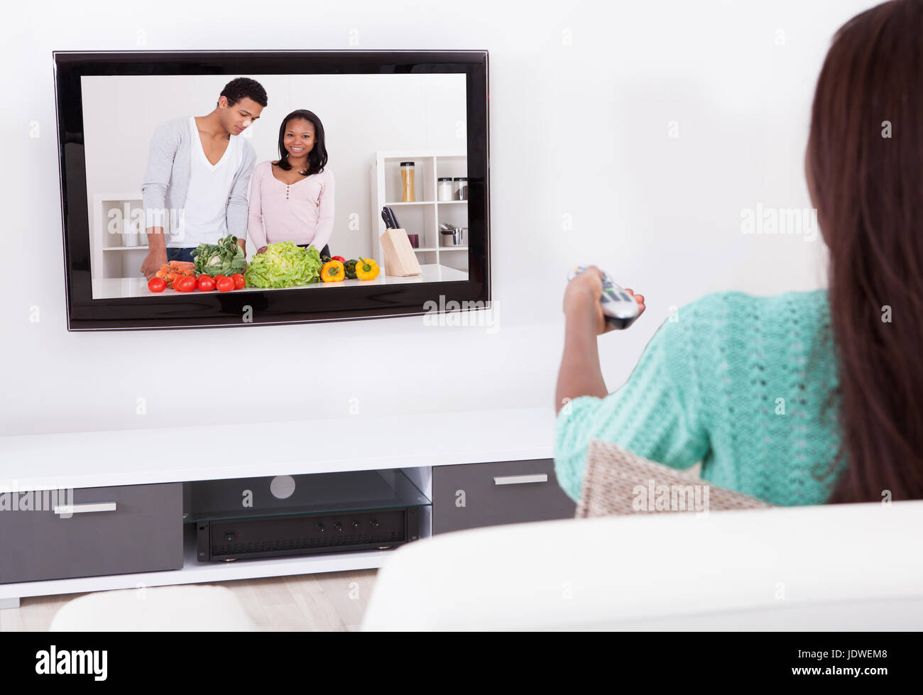 Side view of young woman watching TV in living room Stock Photo - Alamy