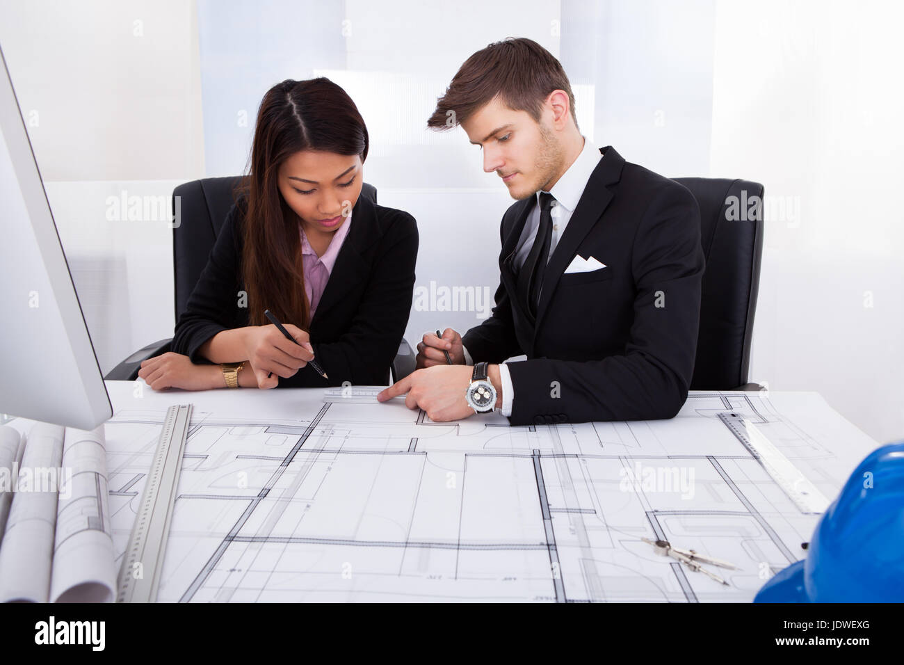Young architects working together on blueprint at desk in office Stock ...