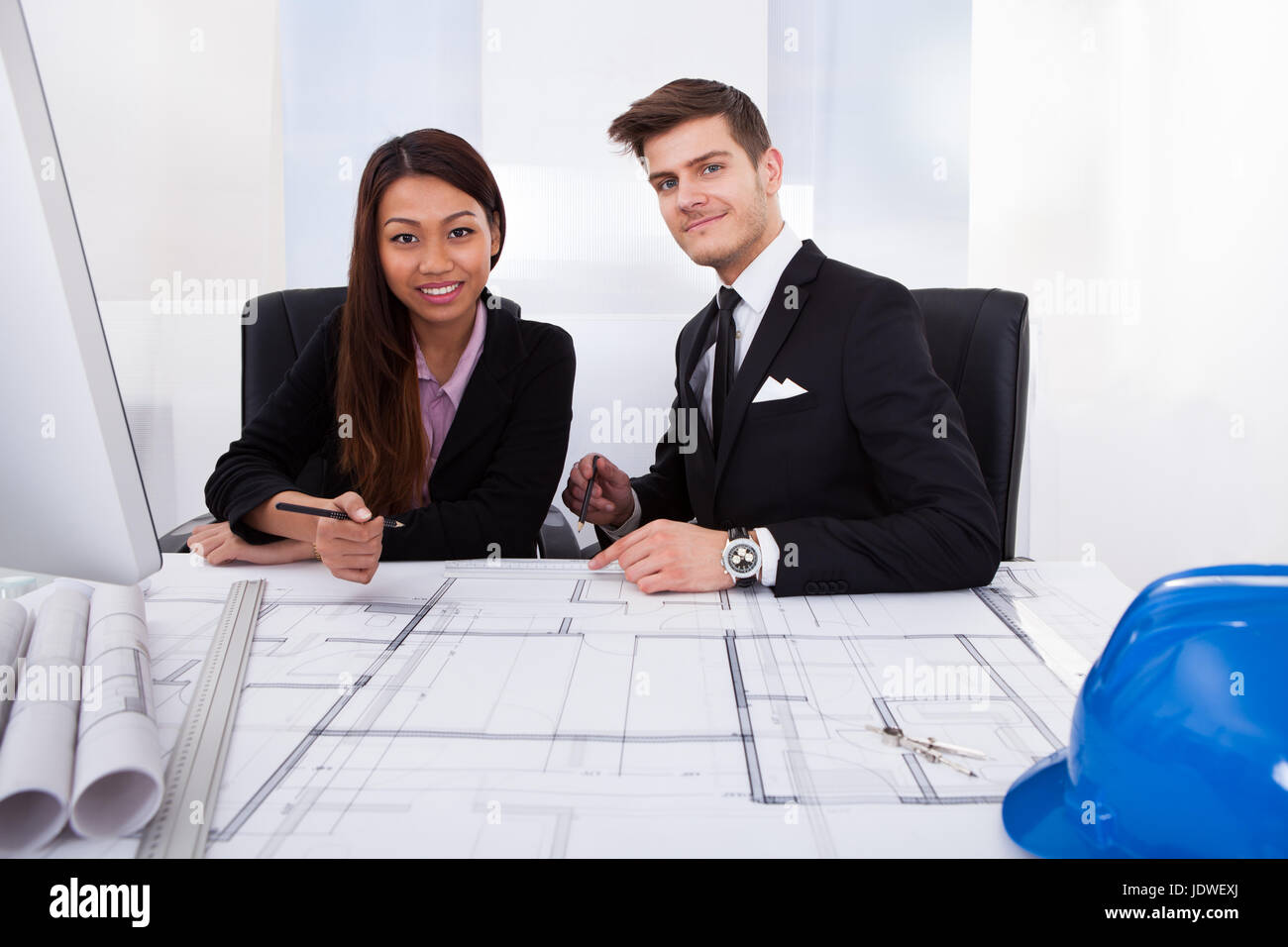 Young architects working together on blueprint at desk in office Stock ...