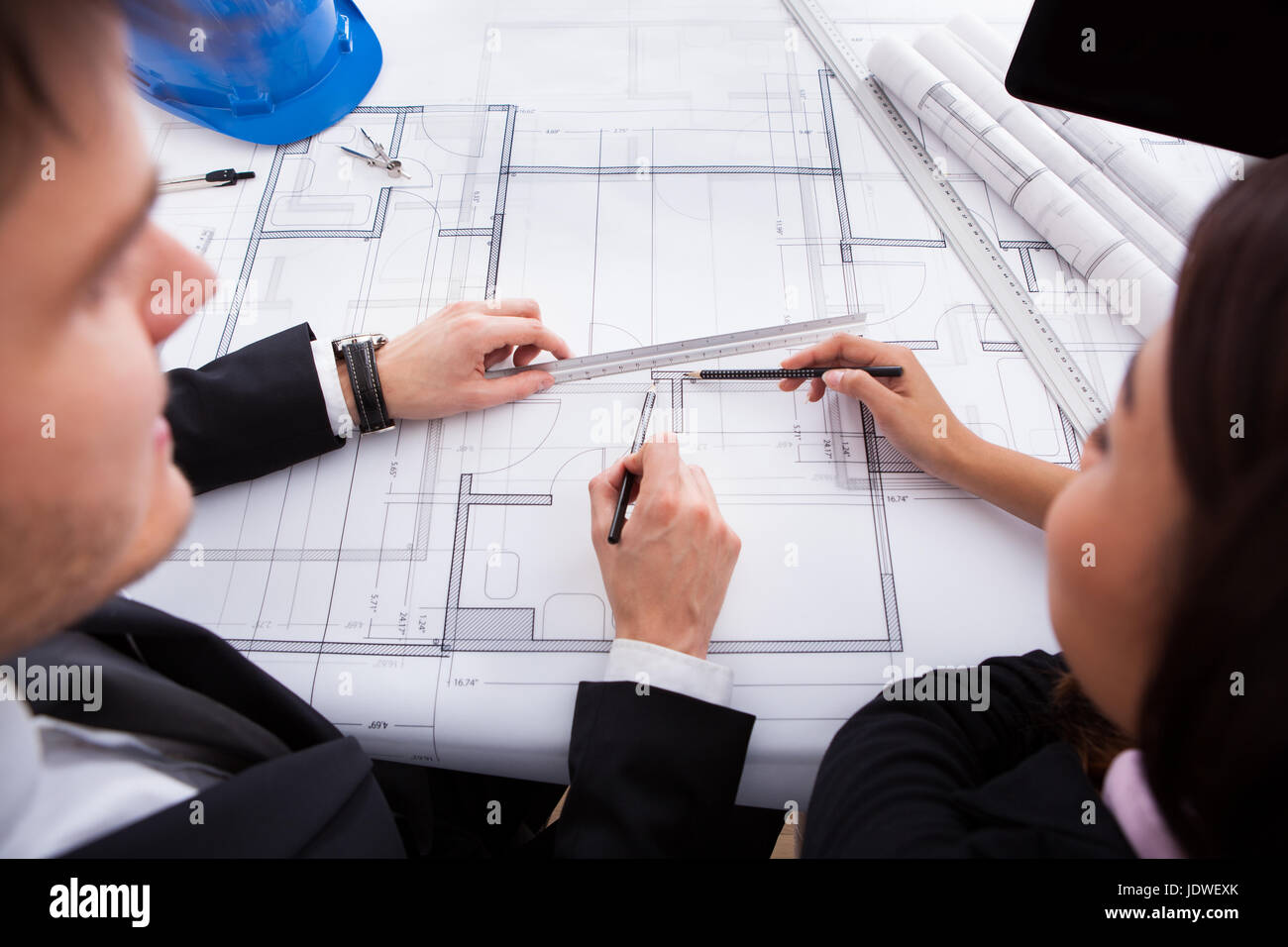 Cropped image of architects working on blueprint at desk in office ...