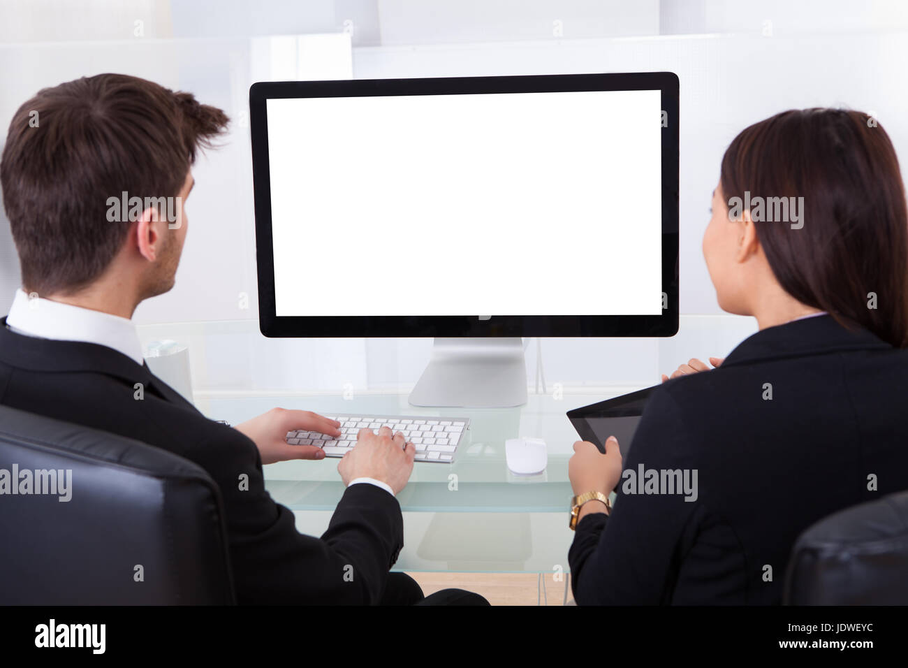 Rear view of business colleagues using computer at desk in office Stock ...
