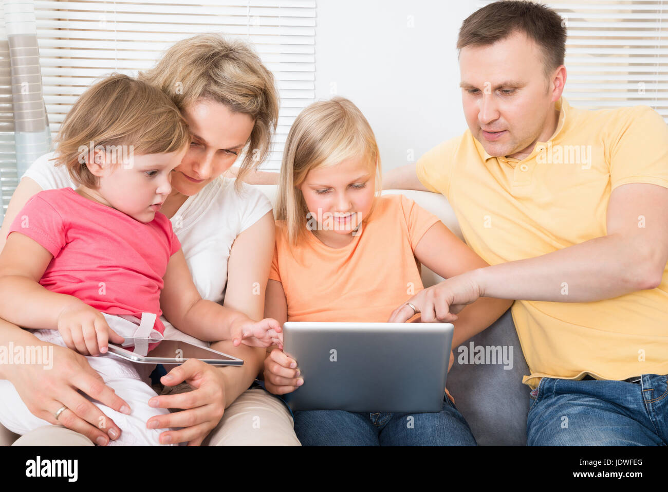 Young Family Using Tablet Together At Home Stock Photo - Alamy