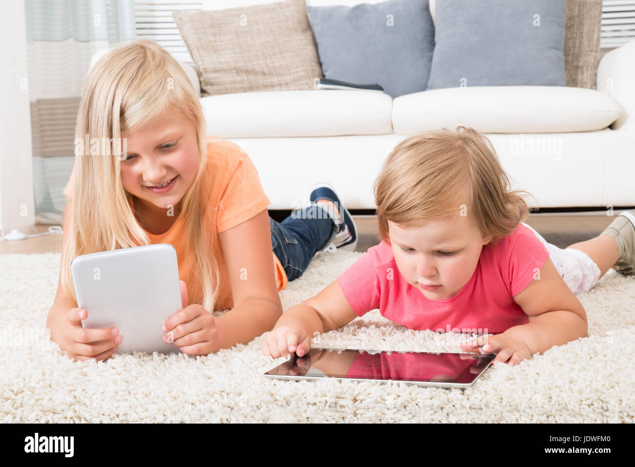 Kids Using Tablet Lying On Carpet At Home Stock Photo - Alamy