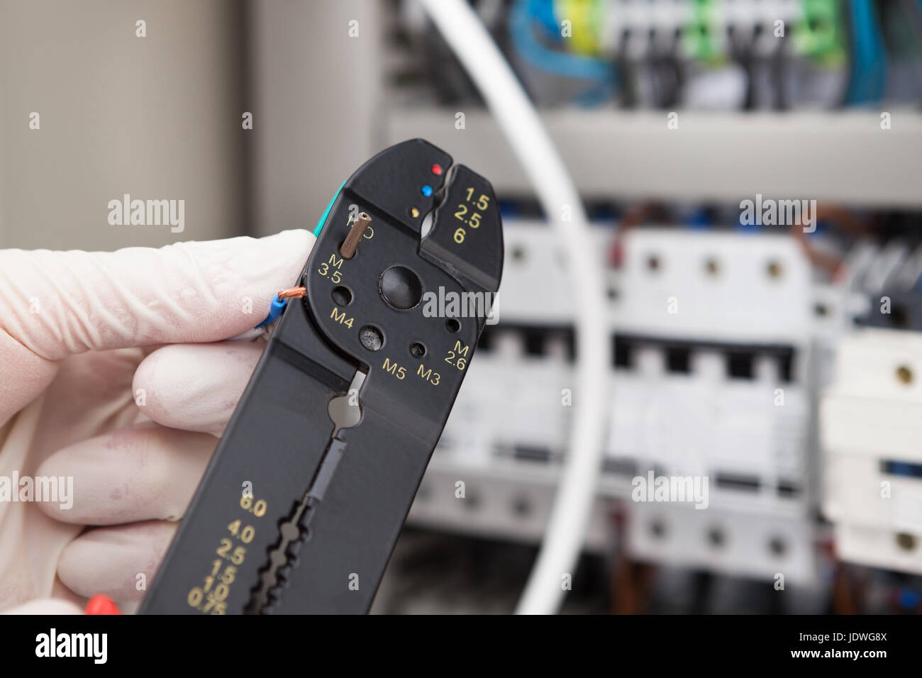 Cropped image of male electrical engineer cutting cable with fusebox in ...